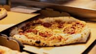 Vastapaistettu pizza on asetettu pakkauslaatikkoon. 