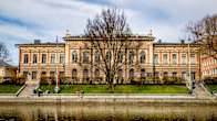 Några människor sitter på kajkanten invid Åbo stadshus.