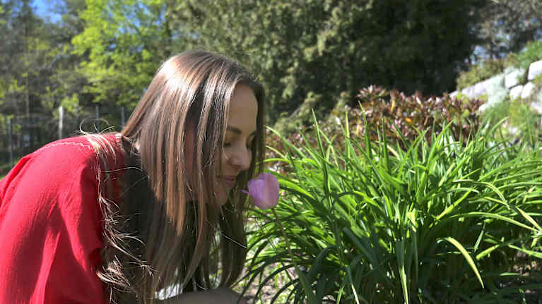 Punaisiin pukeutunut nainen haistaa vaaleanpunaista tulppaania.