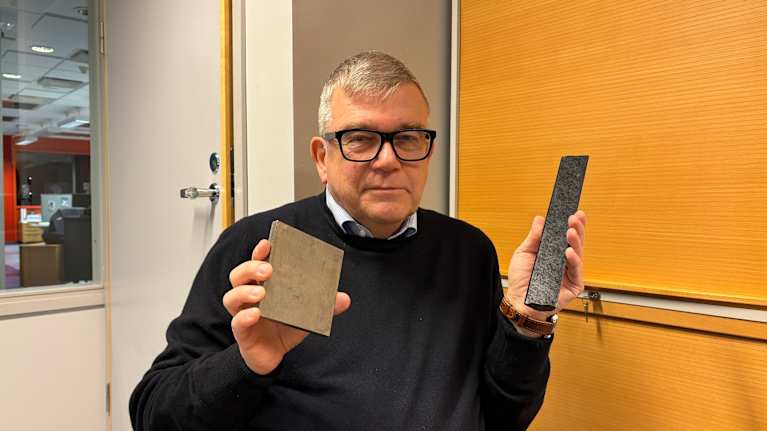 Kuvassa geologi ja kaivosyrittäjä Markus Ekberg. Hänellä on toisessa kädessään tumma, pitkä pala ilmeniittimalmia ja toisessa kädessä vaalea, neliskanttinen metallinen titaanipala.