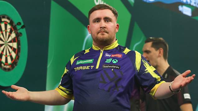 Dartsin pelaaja Luke Littler levittelee käsiään ja katsoo keskittyneesti eteensä.