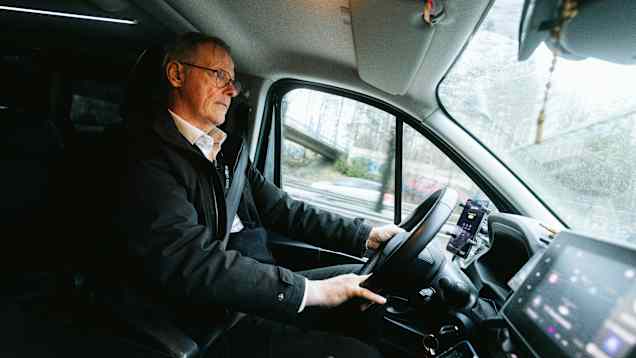 Henkilö istuu tila-auton ohjaamossa.