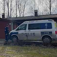 Poliisiauto ja virkapukuinen poliisi rivitaloalueella.