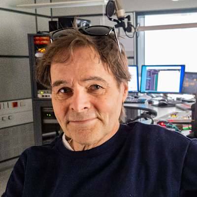 En man i mörk tröja sitter i en radiostudio.