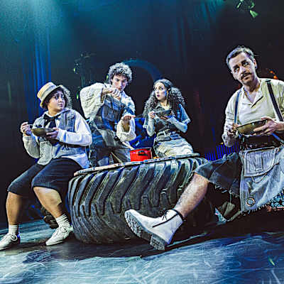 Två män och två kvinnor i senkostyner och med sopptallrikar sitter runt ett traktordäck.