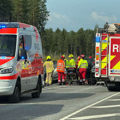 Ambulans och brandbil och en bil i diket med räddningspersonal runt.