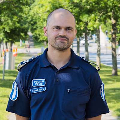 En polis i kortärmad uniformsskjorta står mitt i en esplanad.